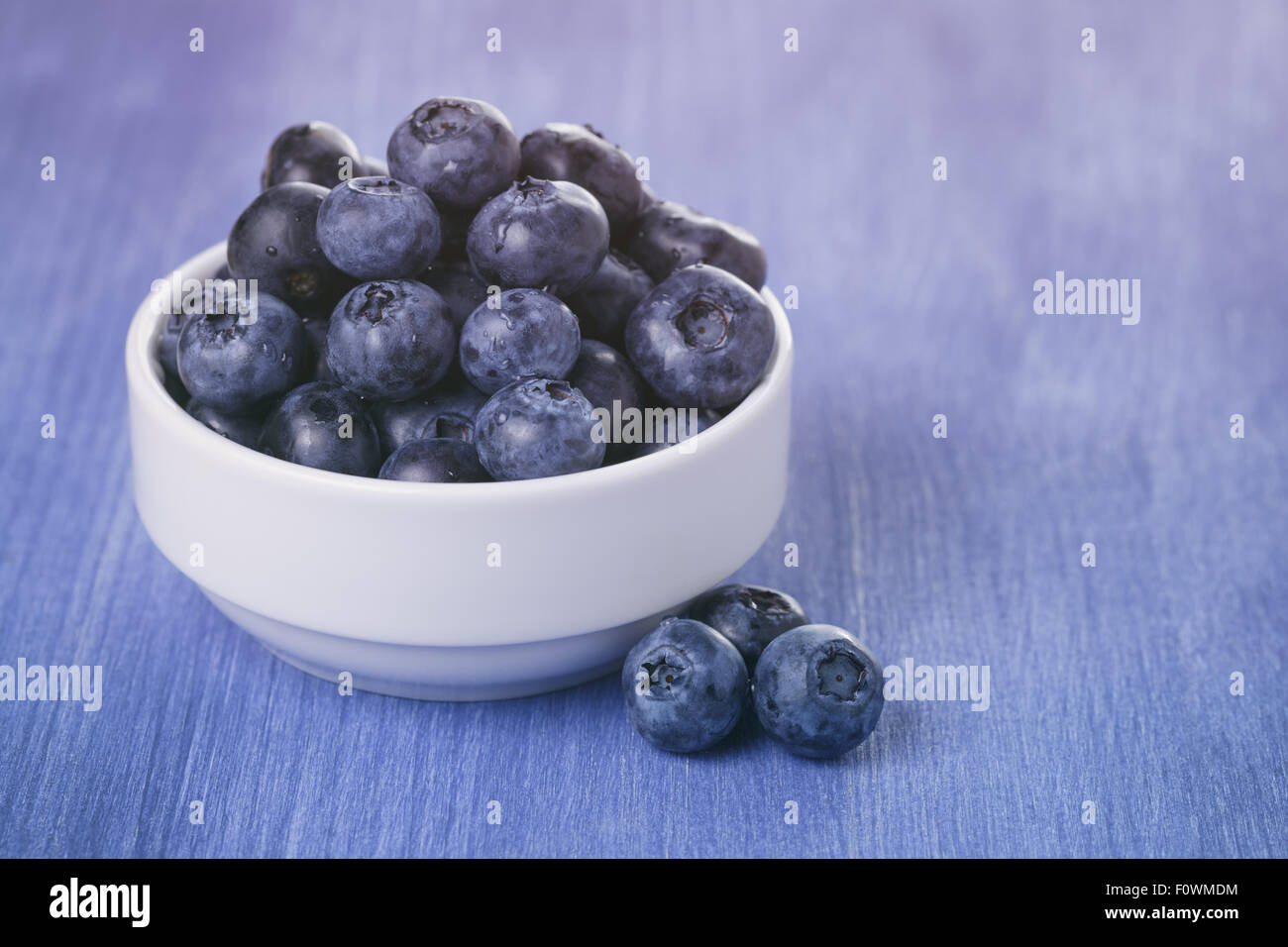 fresh blueberries in bowl on blue wood table Stock Photo - Alamy