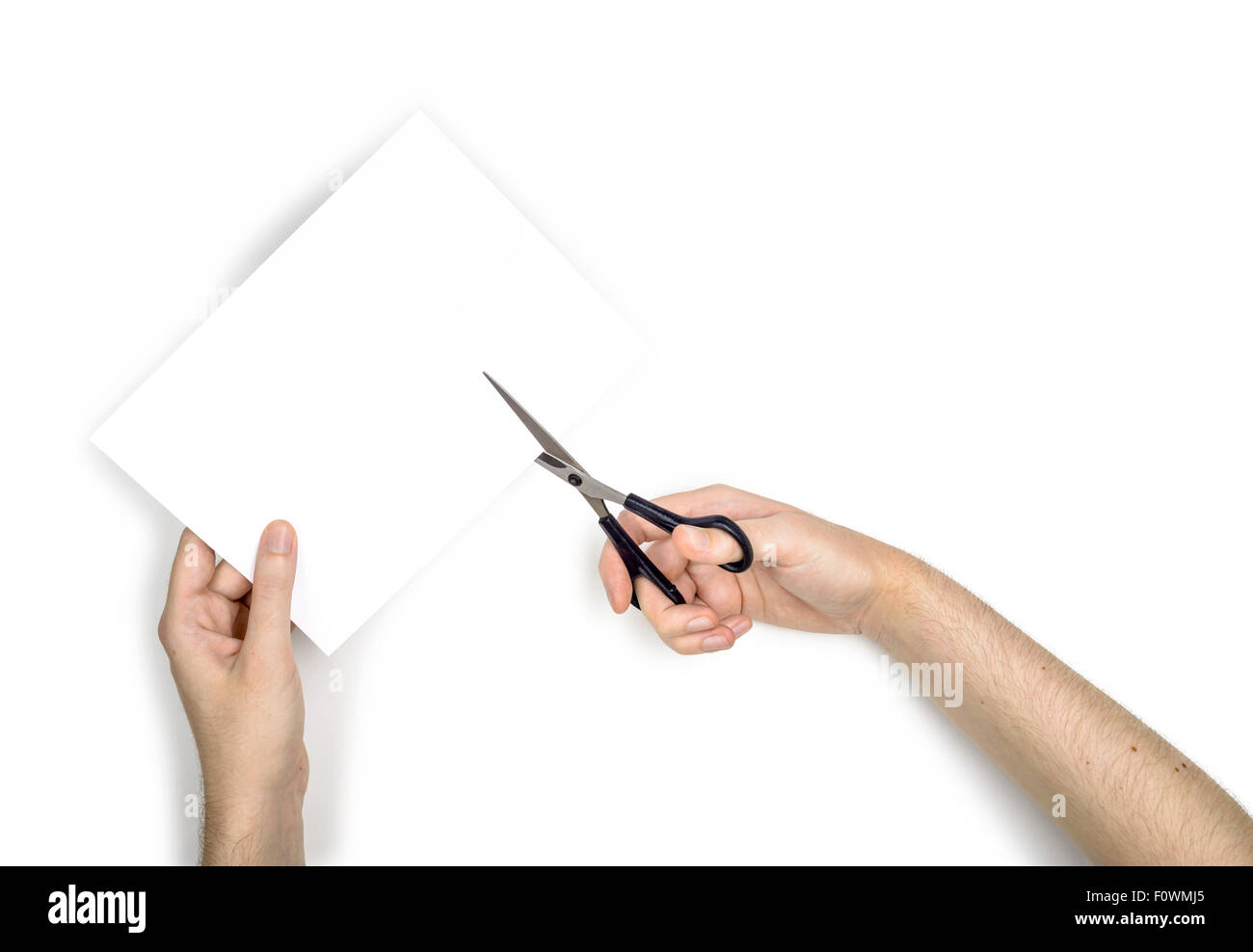 A woman is cutting a sheet of white paper using metallic scissors ...