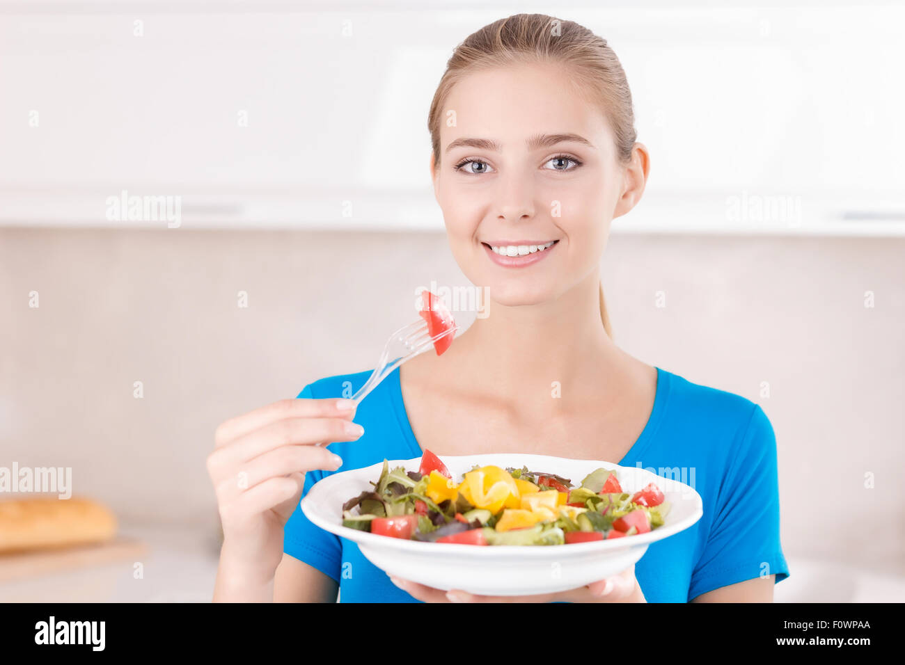 Smiling girl eating salad Stock Photo - Alamy