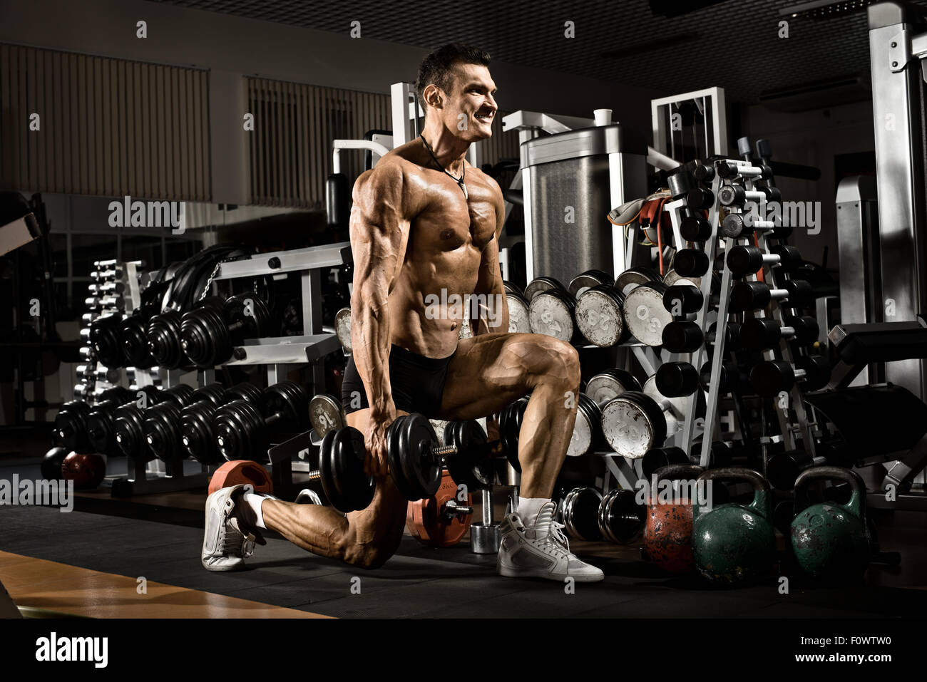 very power athletic guy , execute exercise with dumbbells, in gym Stock ...