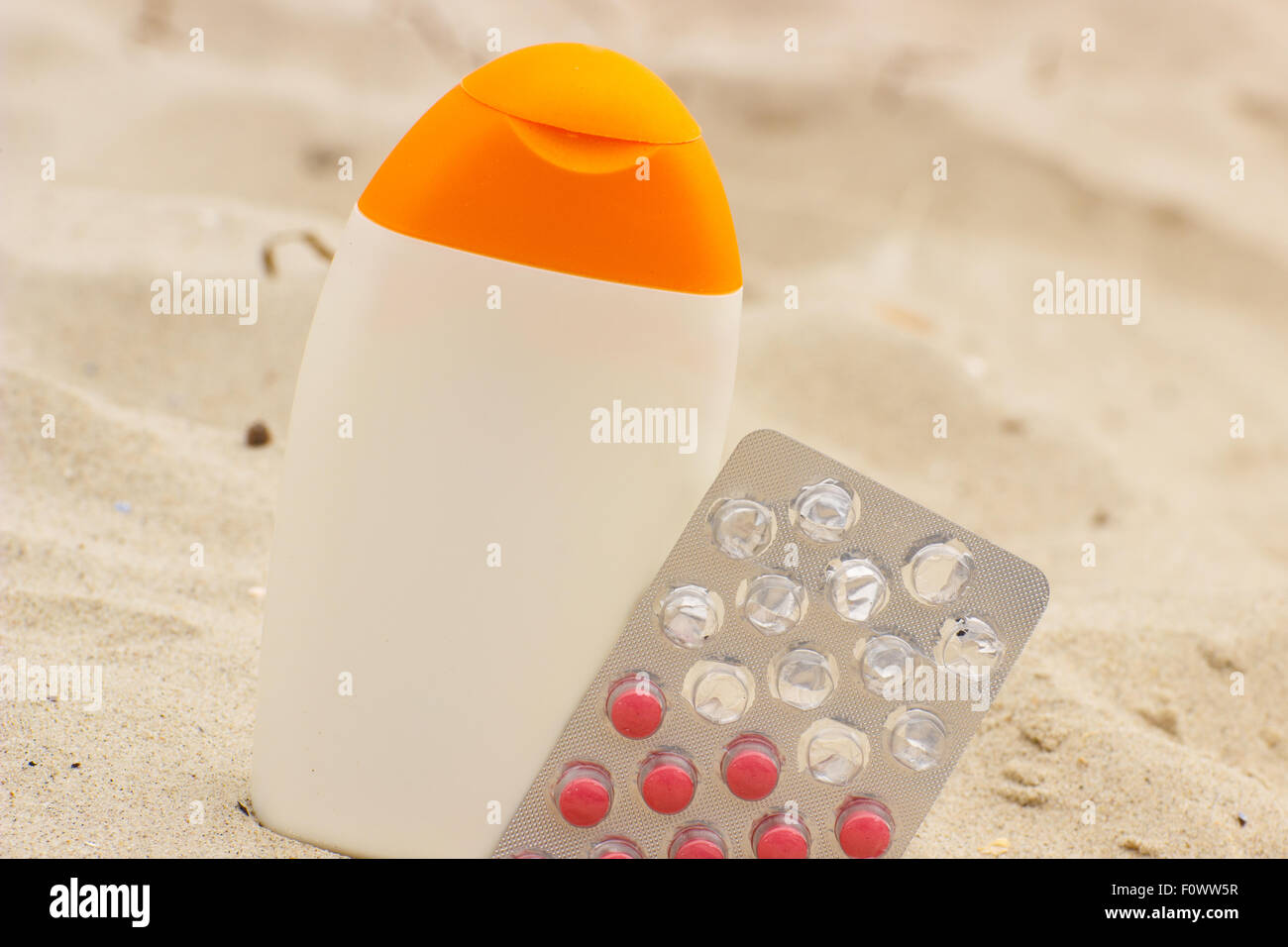 Bottle of sun lotion and pills of vitamin A on sand at the beach ...