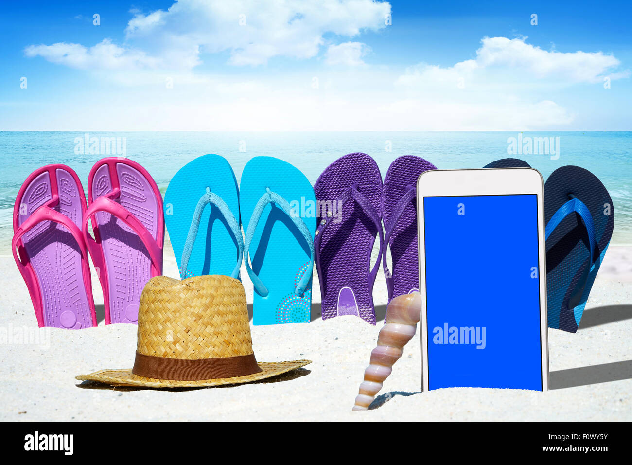 White smartphone with blank screen display, flip flops and a straw hat ...