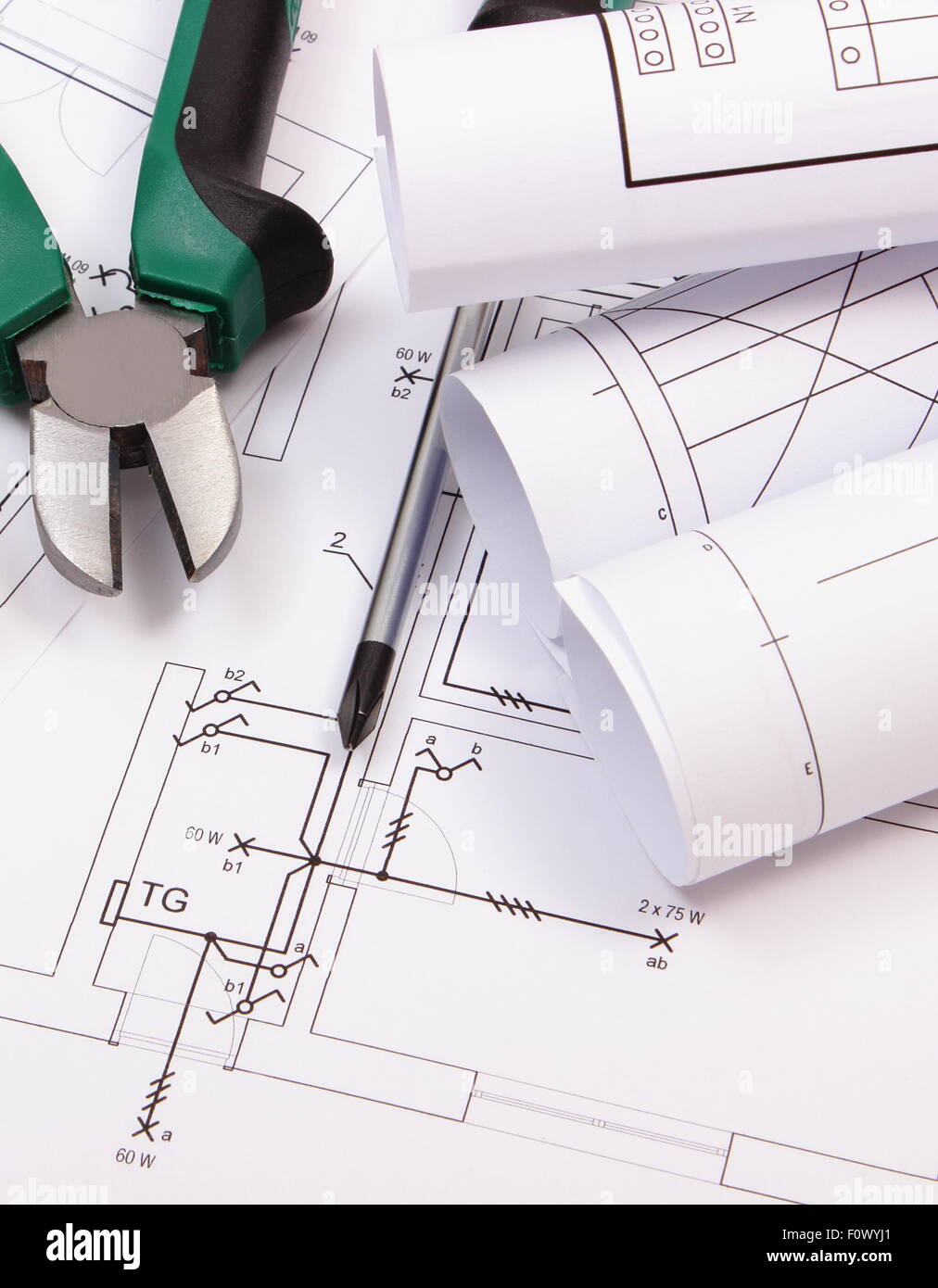 Metal pliers, screwdriver and rolls of diagrams on electrical ...