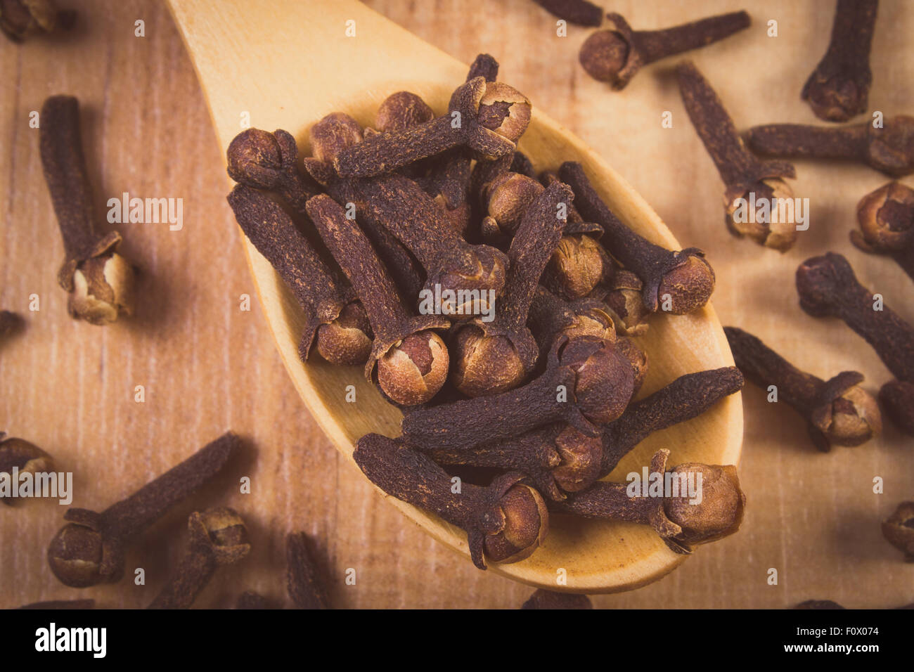 Vintage photo, Heap of brown cloves on wooden spoon lying on wooden ...