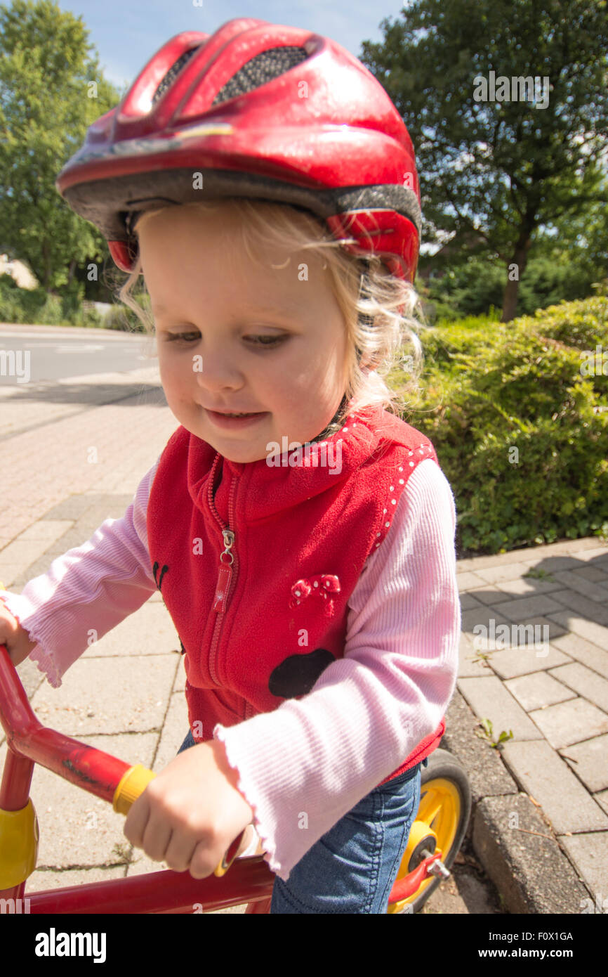 Little girl on bike on the pavement with crash helmet Stock Photo - Alamy