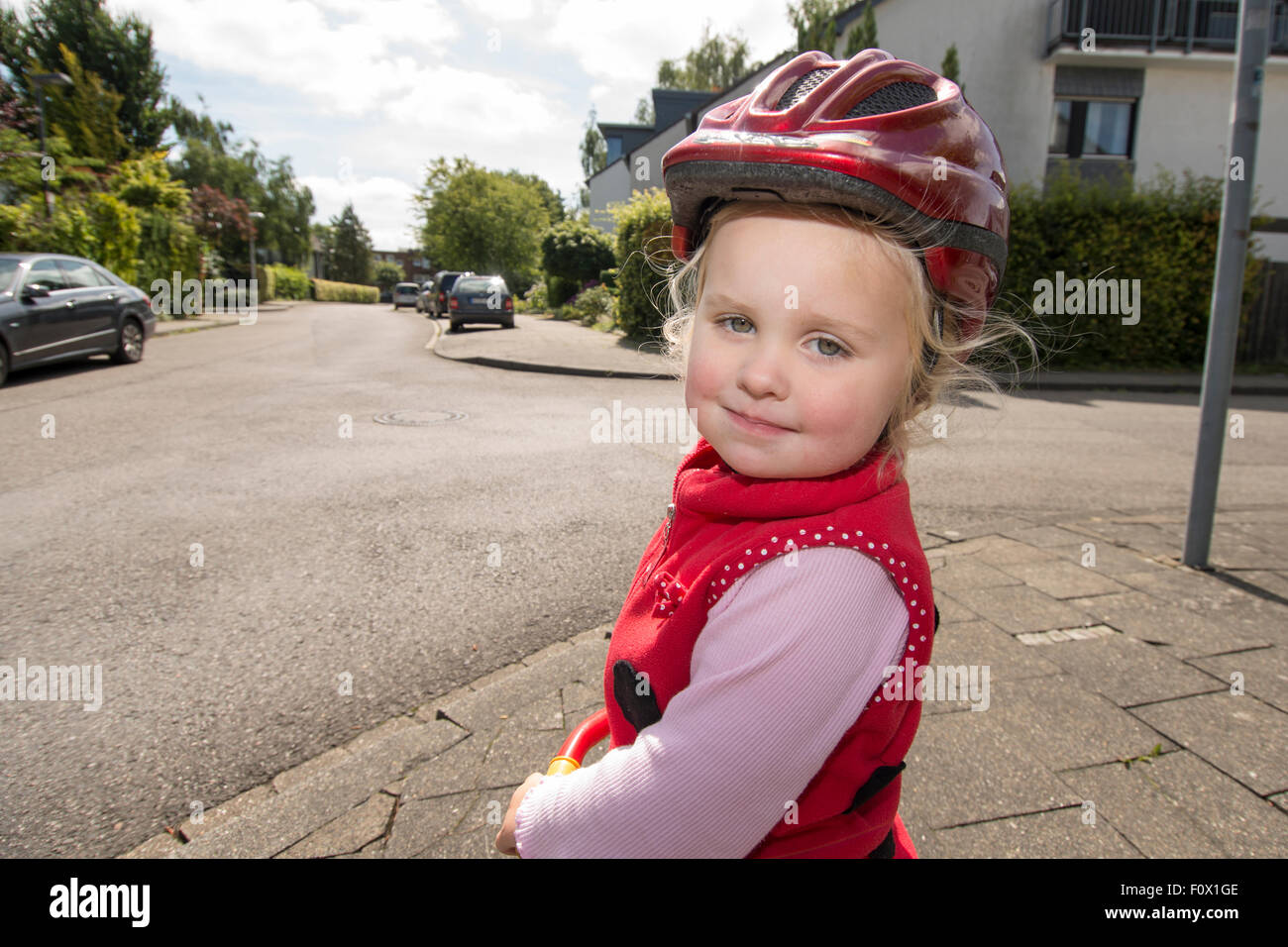 Little girl on bike on the pavement with crash helmet Stock Photo - Alamy