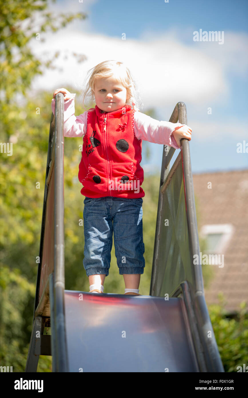 Little girl standing at the top of a slide Stock Photo - Alamy