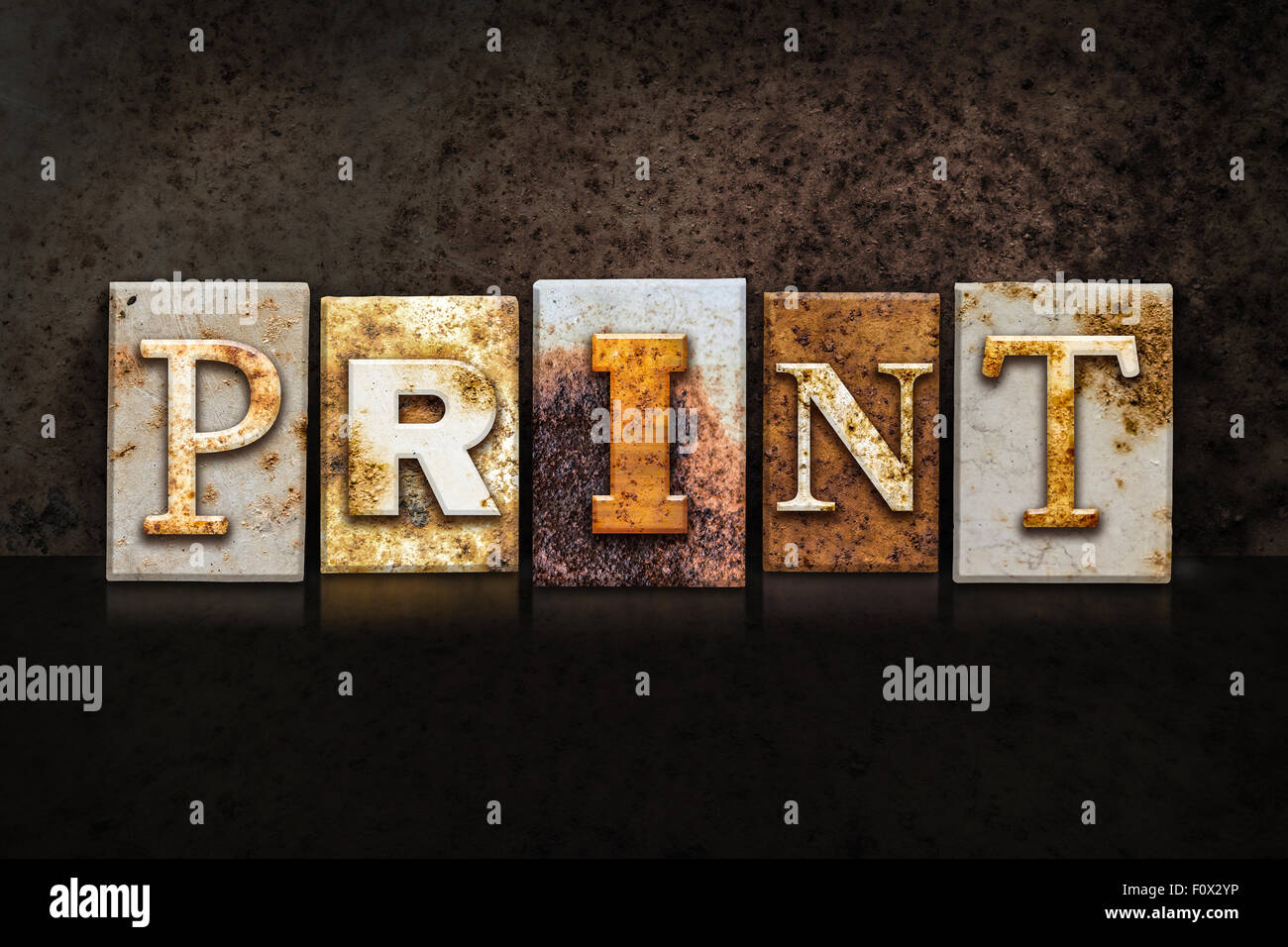 The word "PRINT" written in rusty metal letterpress type on a dark ...