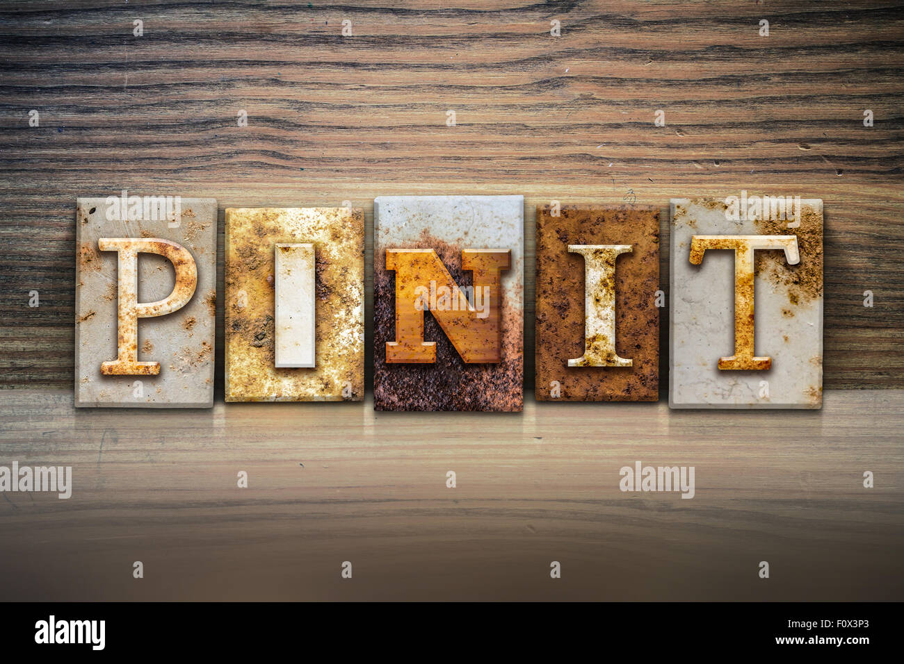 The word "PIN IT" written in rusty metal letterpress type sitting on a ...