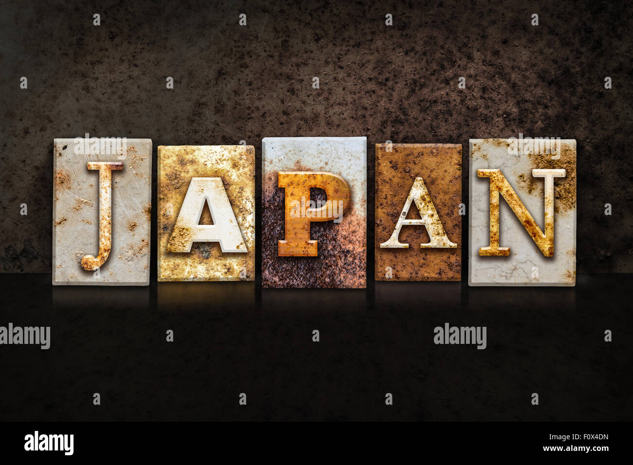 The word "JAPAN" written in rusty metal letterpress type on a dark ...