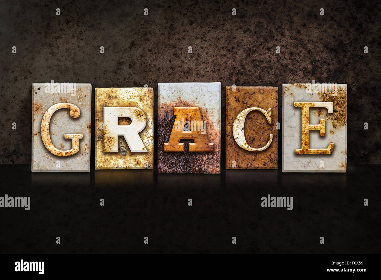 The word "GRACE" written in rusty metal letterpress type on a dark ...