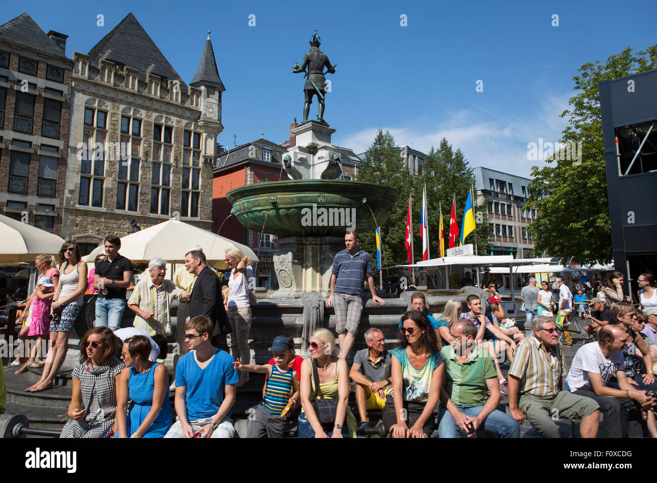 People relaxing in the sun on a fountain in the city center of Aachen ...
