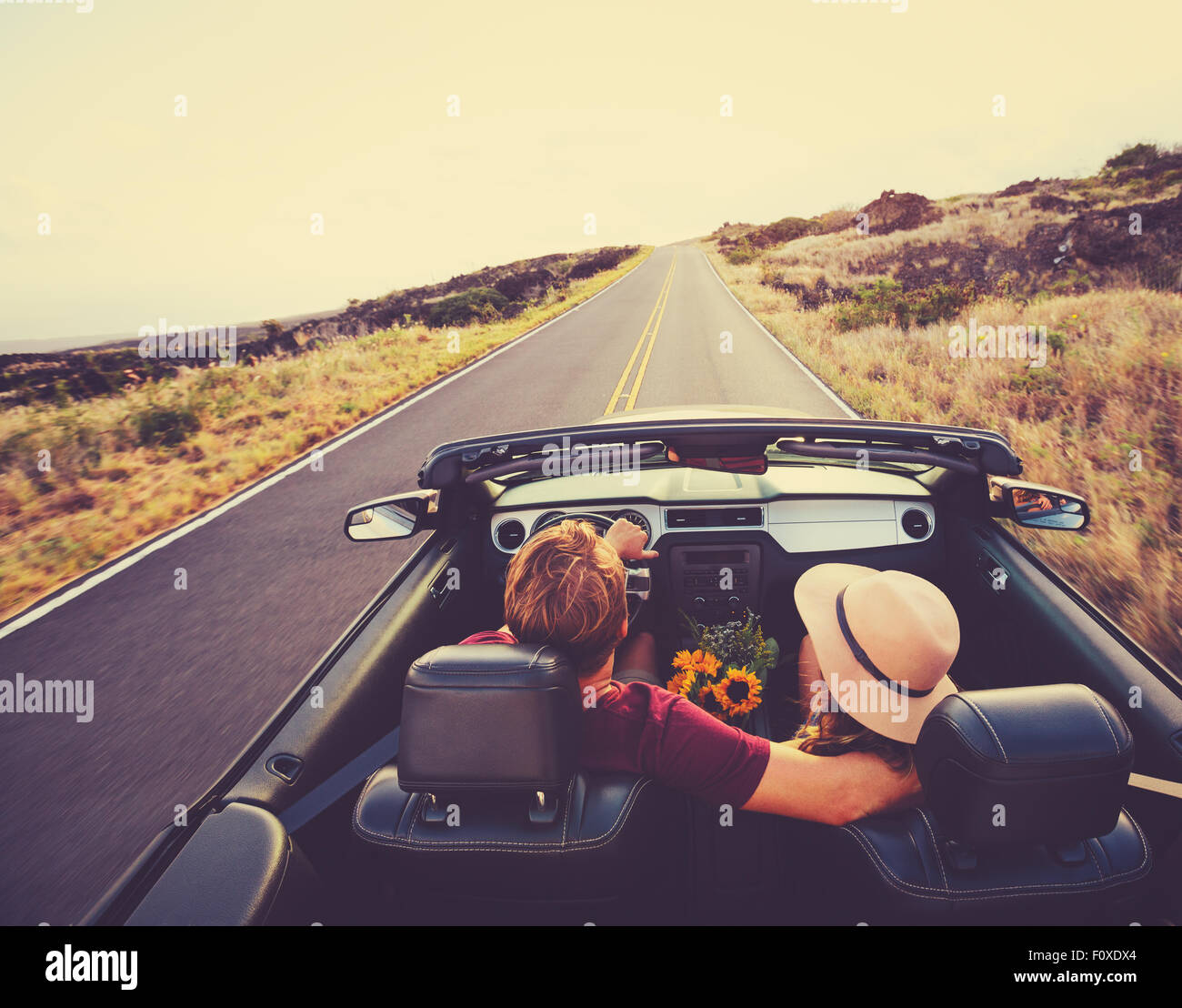 Happy Young Couple Driving Along Country Road in Convertible at Sunset ...