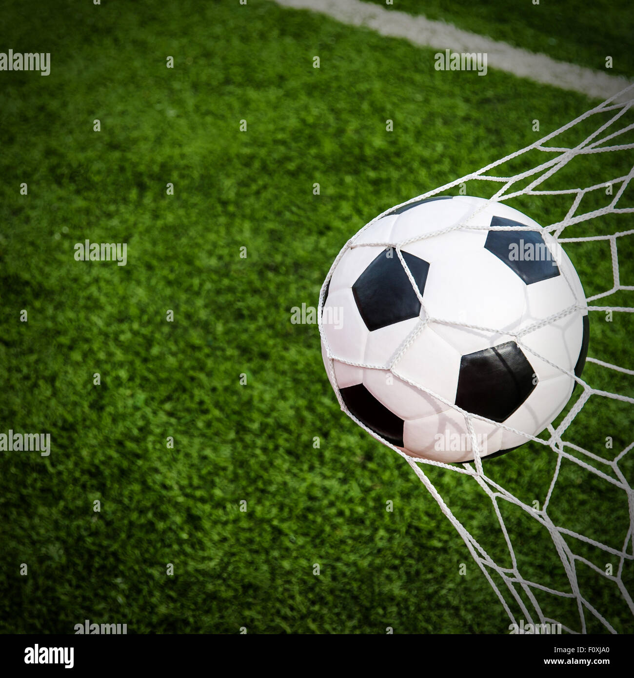 Soccer football in Goal net with green grass field Stock Photo - Alamy