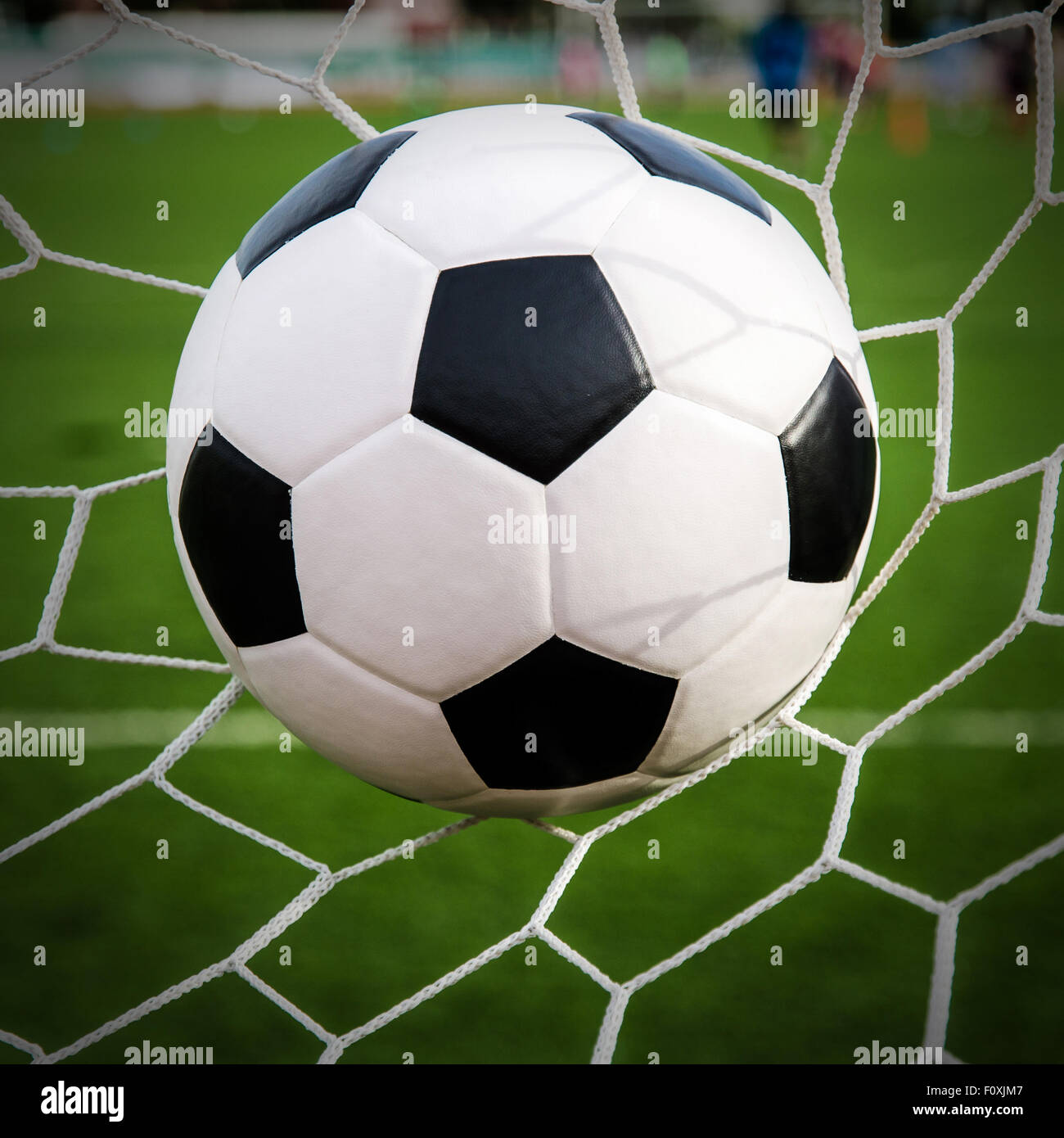 Soccer football in Goal net with green grass field. For sport concept ...