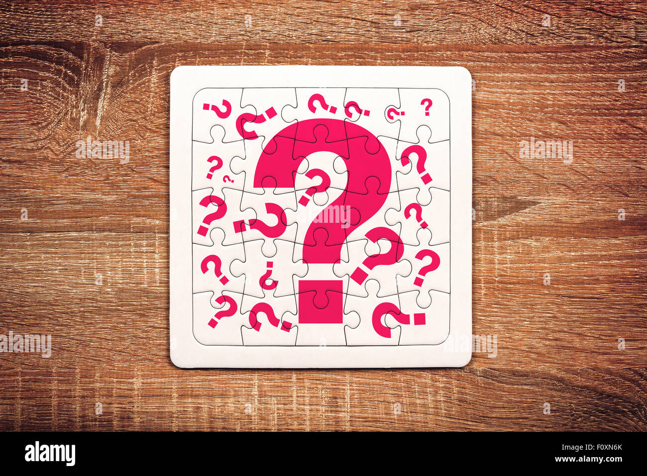 Question marks on completed jigsaw puzzle placed on top of old wooden ...