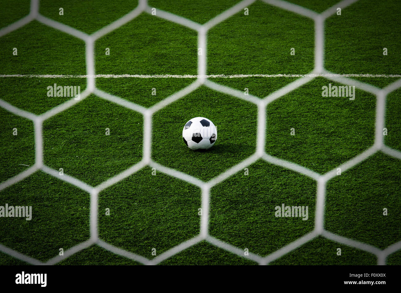 Soccer football in net with green grass field Stock Photo - Alamy