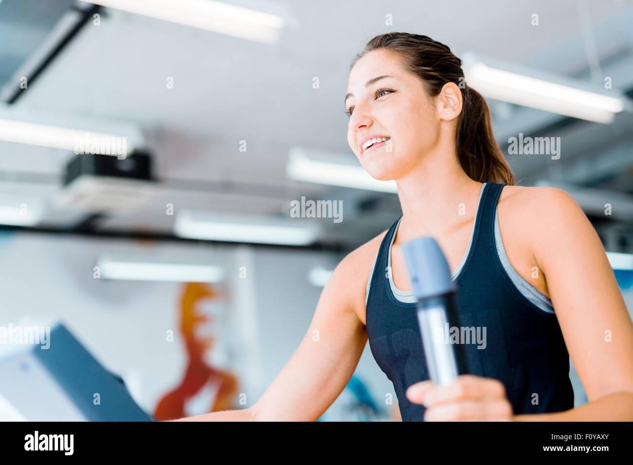 Beautiful young lady using the elliptical trainer in a gym in a ...