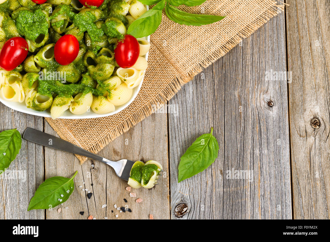Top view of basil pesto with shell shaped pasta and cherry tomatoes on ...