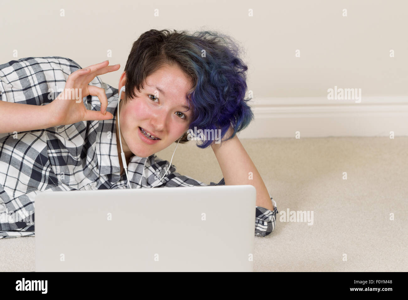Smiling teen girl, looking forward, giving okay sign while using ...