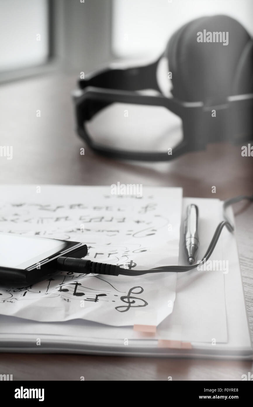 Closeup of smartphone with headphone on musical notes paper on wooden ...