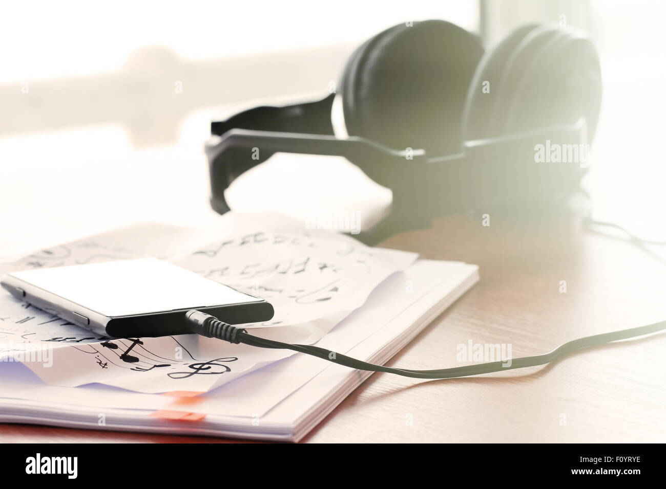 Closeup of smartphone with headphone on musical notes paper with ...