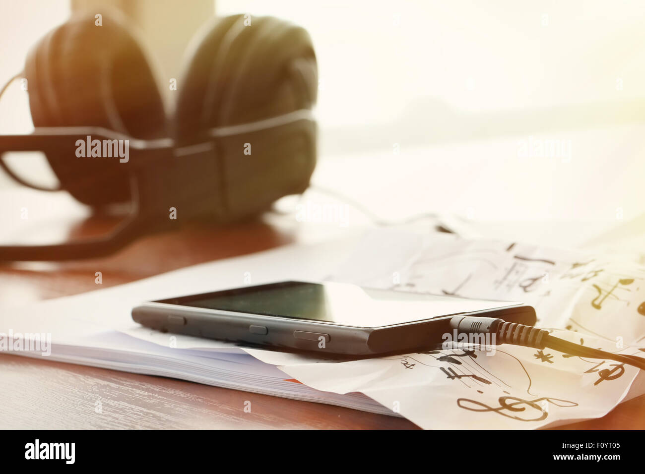 Closeup of smartphone with headphone on musical notes paper with ...