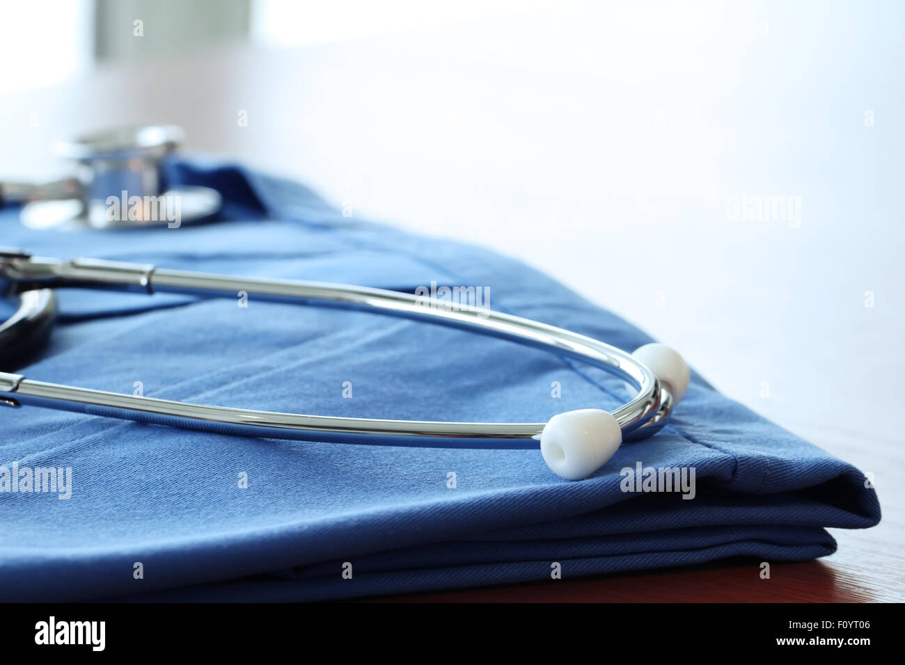 Stethoscope with blue doctor coat on wooden table with shallow DOF ...
