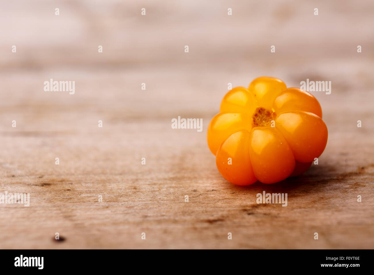 Single cloudberry (moroshka) on a wooden table. Wild northern berry ...