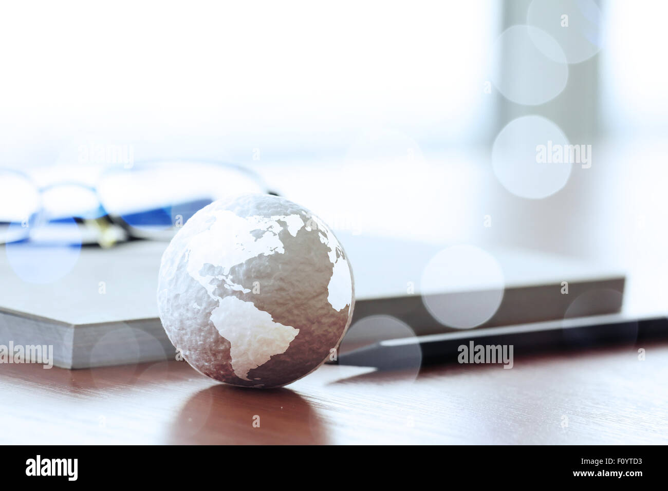 hand drawn texture globe on wood table near note book and glasses with ...