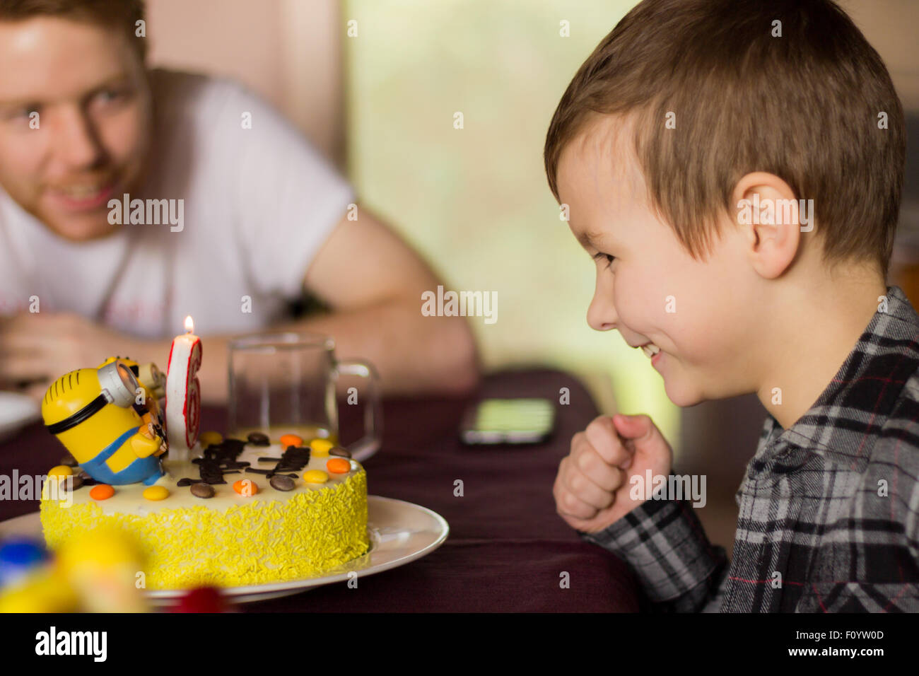 A boy blowing out the candles on his yellow birthday cake Stock Photo ...