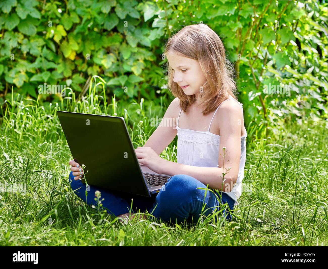 Girl using laptop on grass outdoor Stock Photo - Alamy