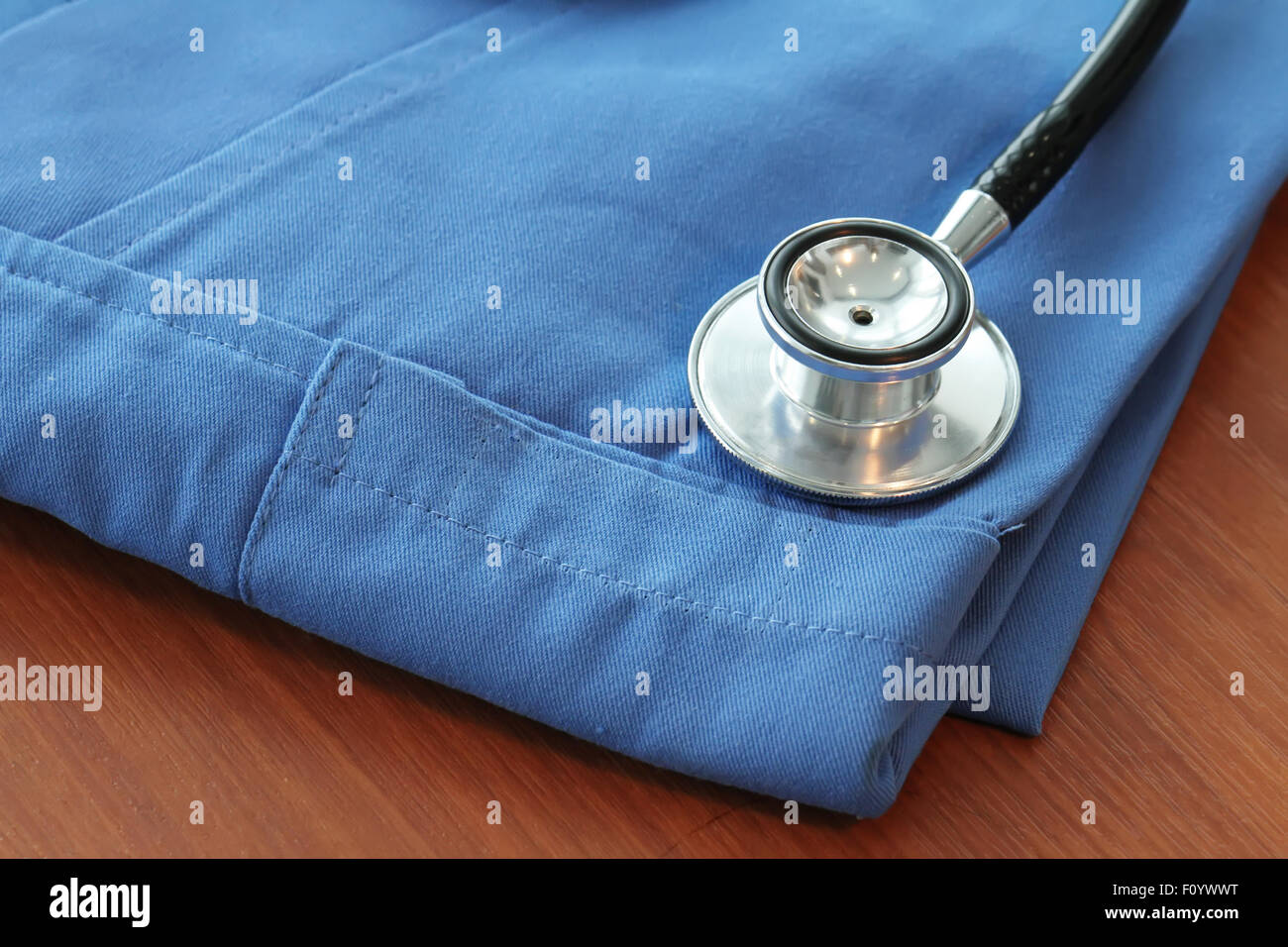 Stethoscope with blue doctor coat on wooden table with shallow DOF ...