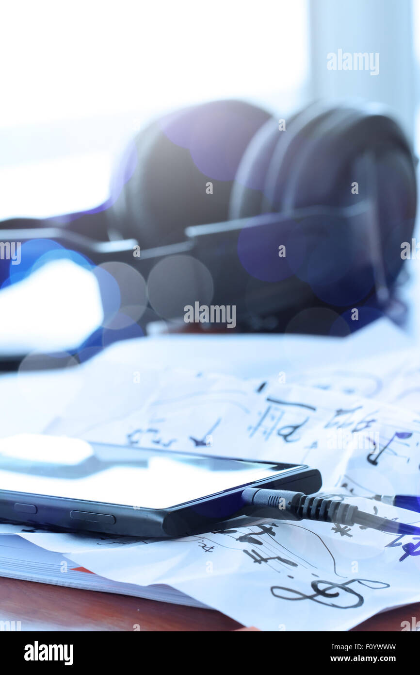 Closeup of smart phone with headphone on musical notes paper with ...