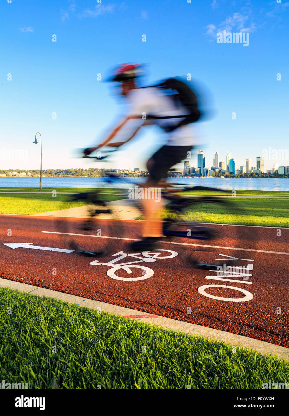 A male cyclist riding down a bike path with a city skyline in the ...