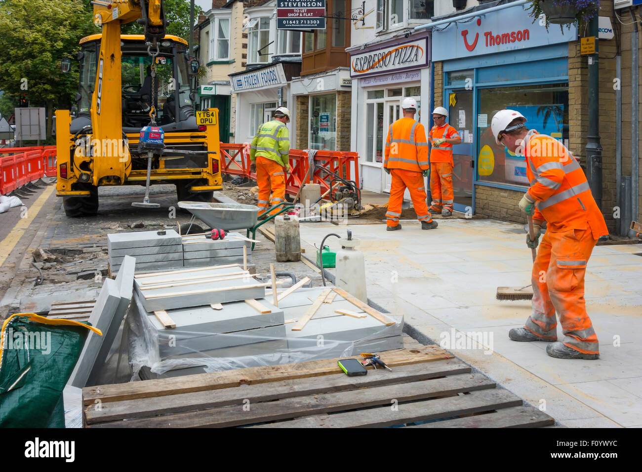 Workman using a JCB excavator laying a new pavement surface in ...