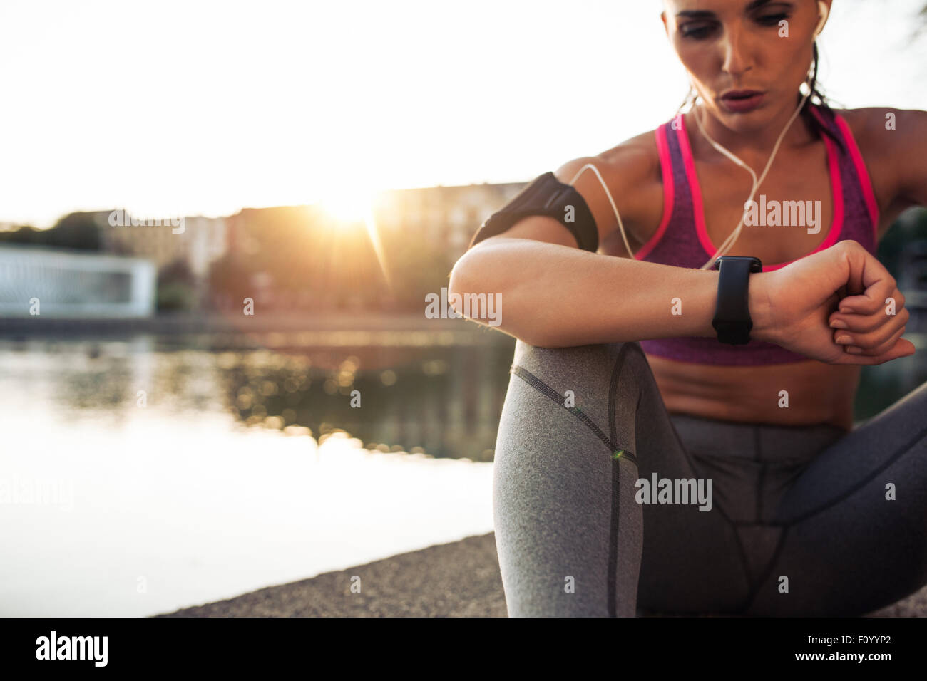 Beautiful young woman sitting outdoors using a smartwatch to monitor ...