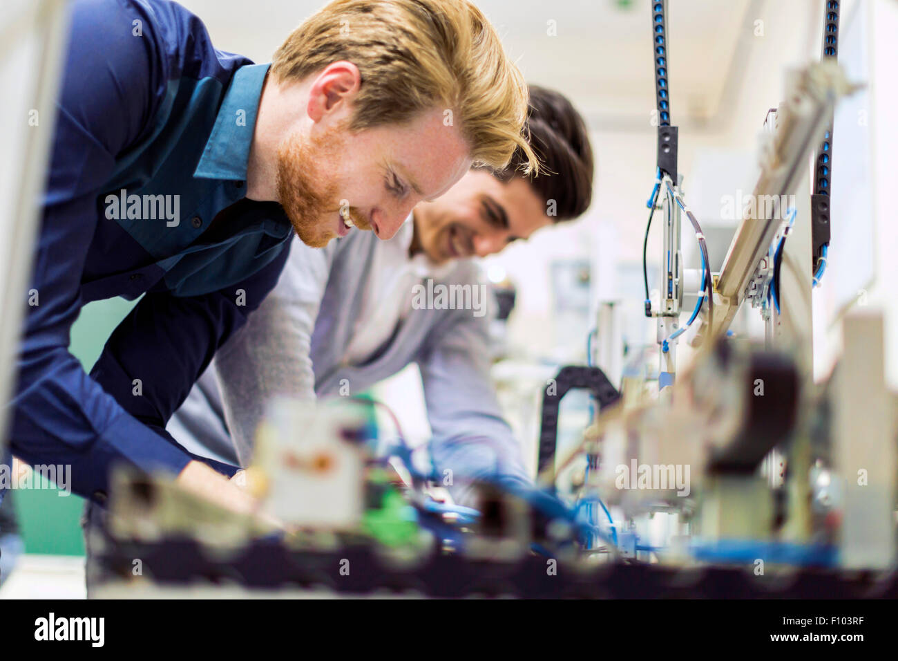 Two young handsome engineers working on electronics components and ...
