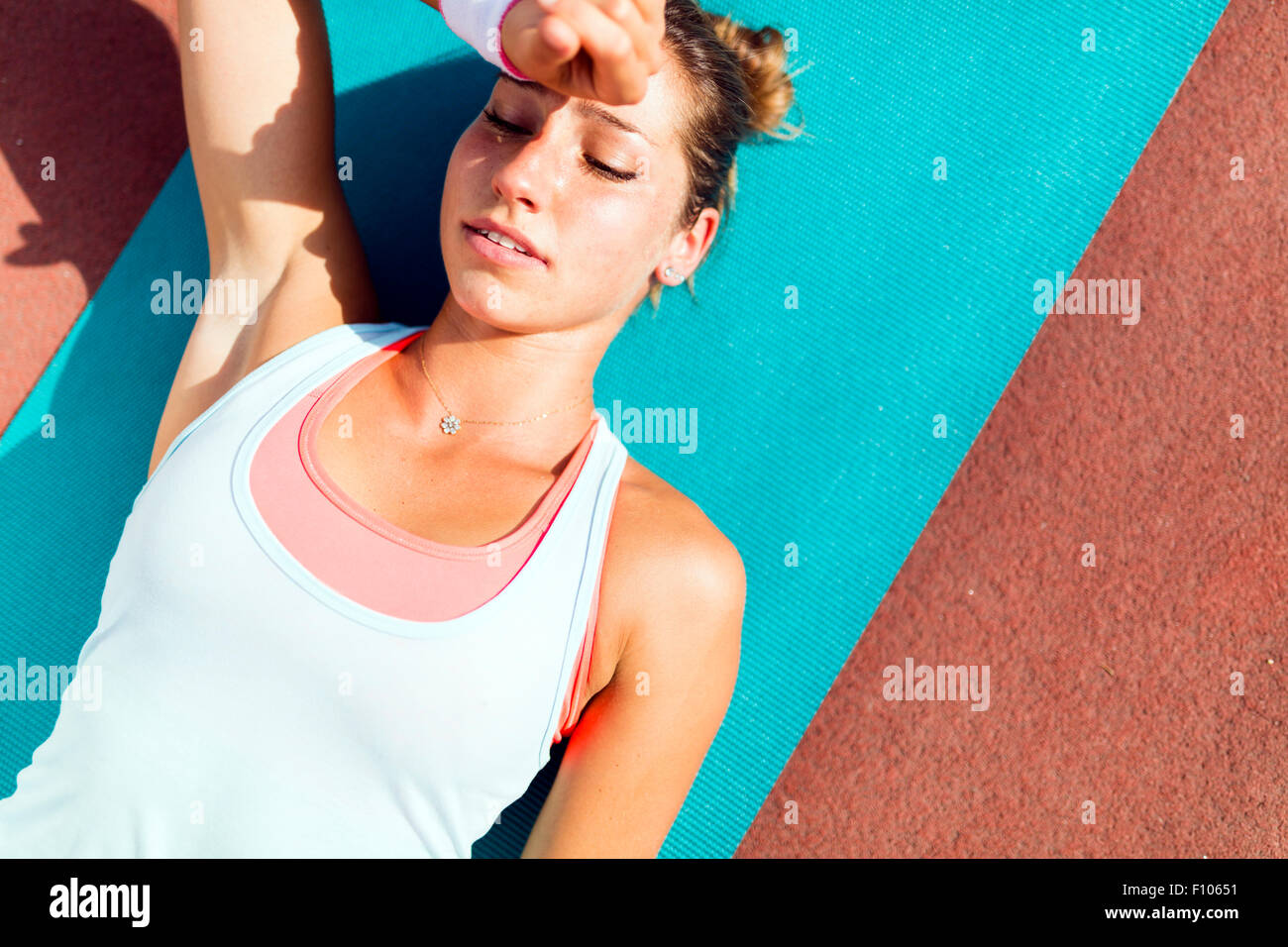 Exhausted Beautiful Young Woman Lying On A Mat After Exercise Stock