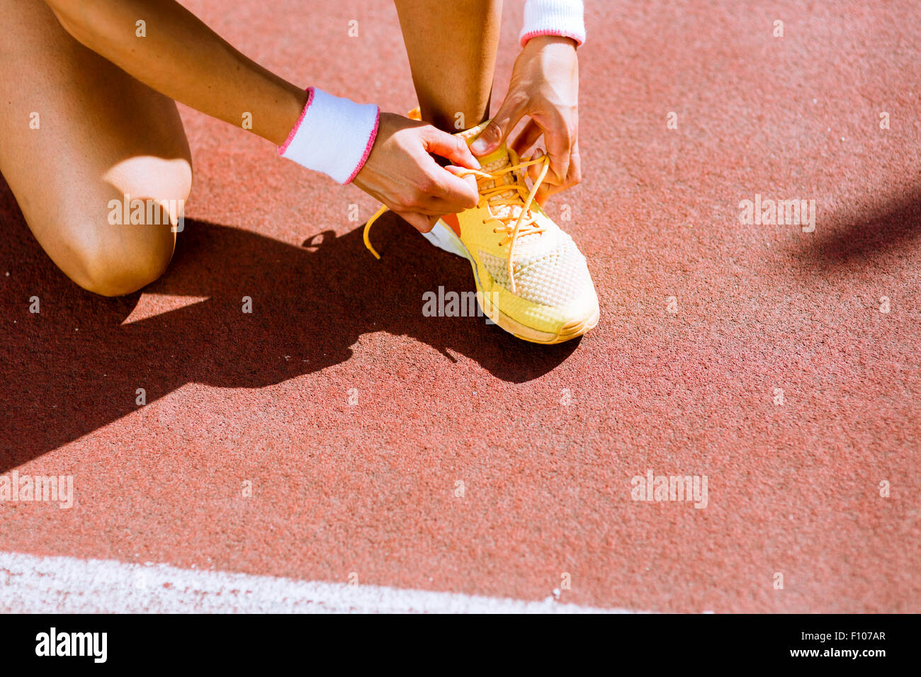 Athlete tying shoe lace with both hands in summer Stock Photo - Alamy