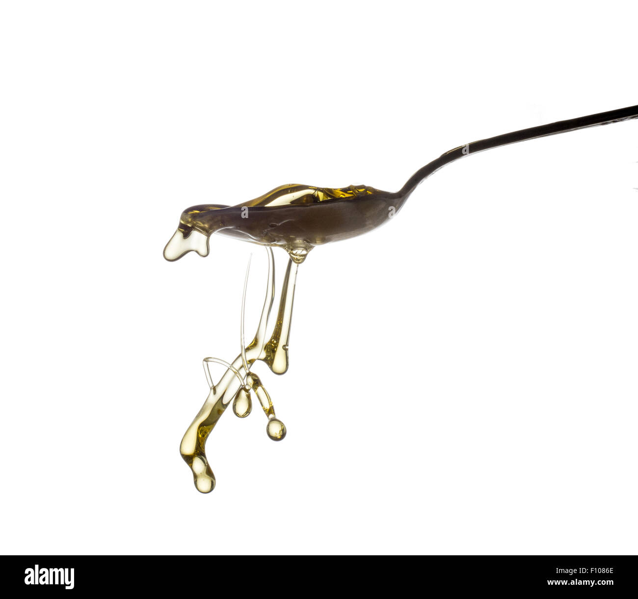Pouring oil splash on spoon isolated Stock Photo - Alamy