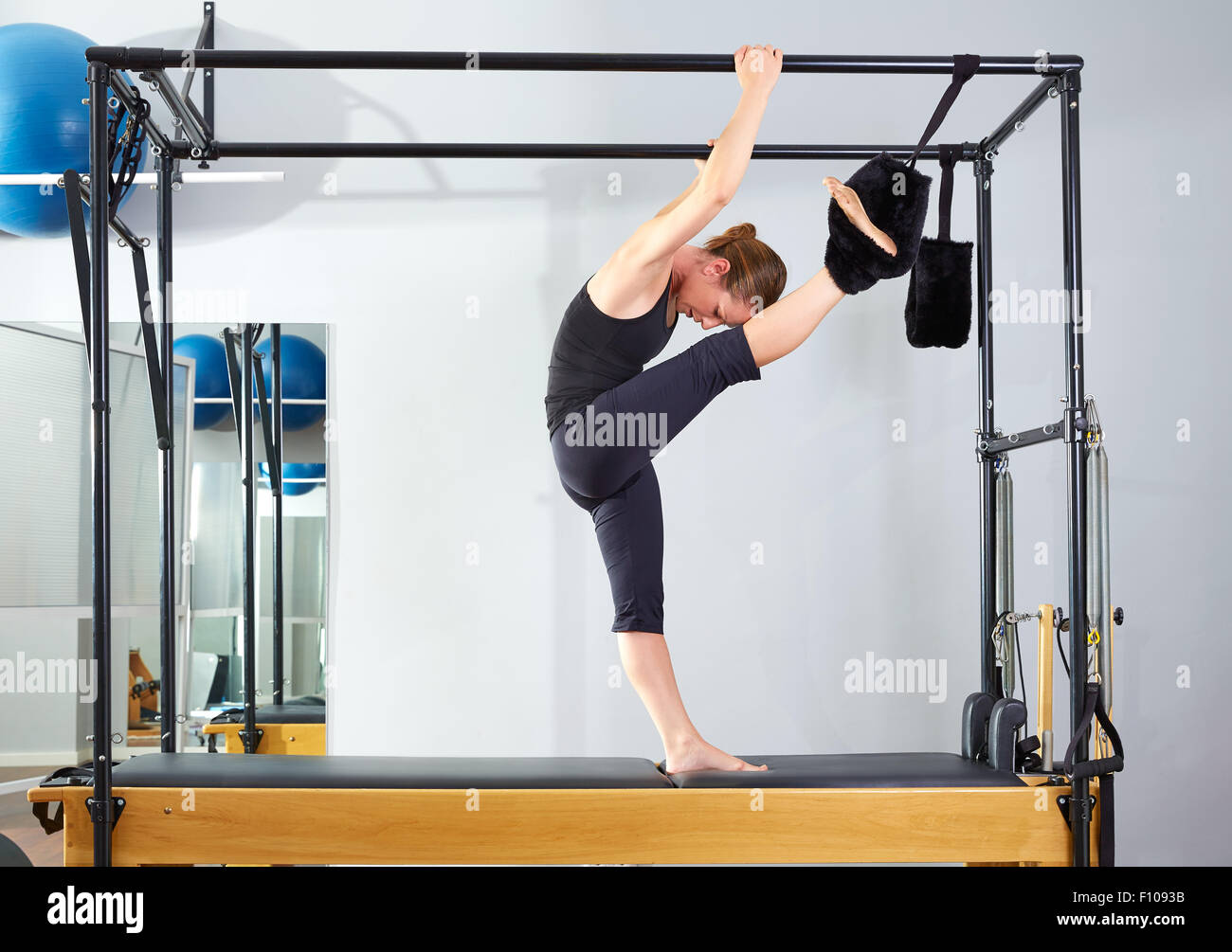 Pilates woman in cadillac split legs stretch exercise at gym Stock ...