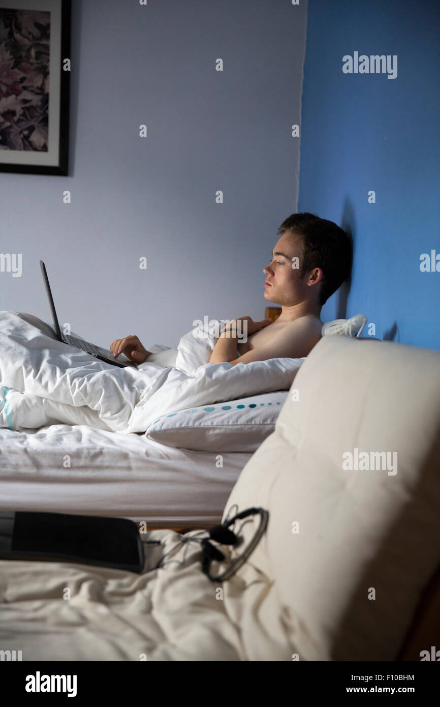 student lying in bed working on laptop Stock Photo - Alamy