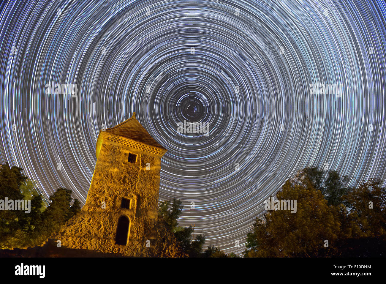long stars trails around north star over ancient castle tower ...