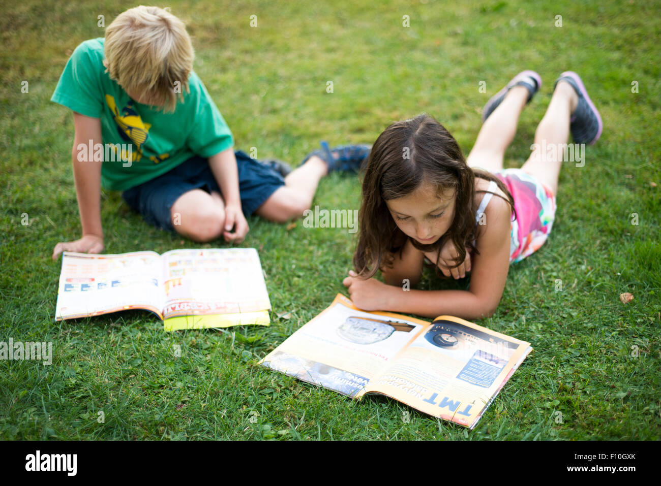 Kids reading together enjoying and reading a magazine laying on the ...