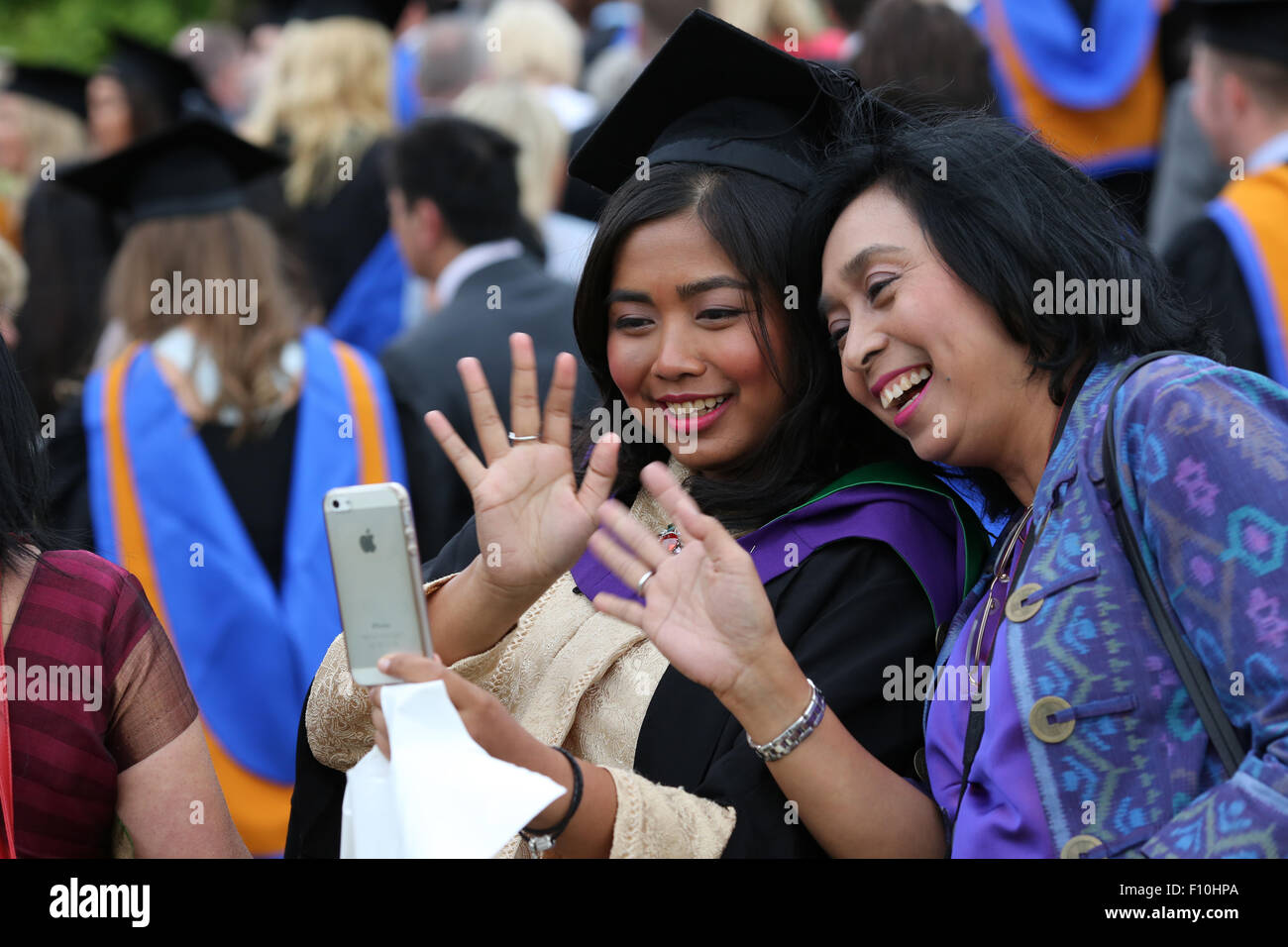 young female graduating students taking photos with their camera phone ...