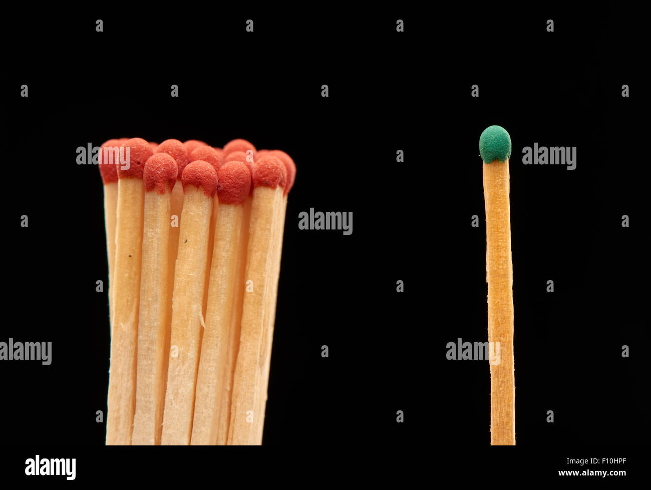Group of red wooden matches standing with green match, isolated on ...