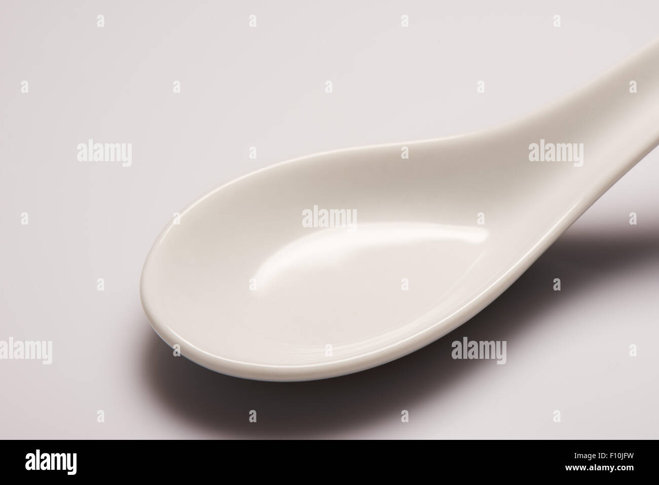 White empty ceramic spoon on white background Stock Photo - Alamy