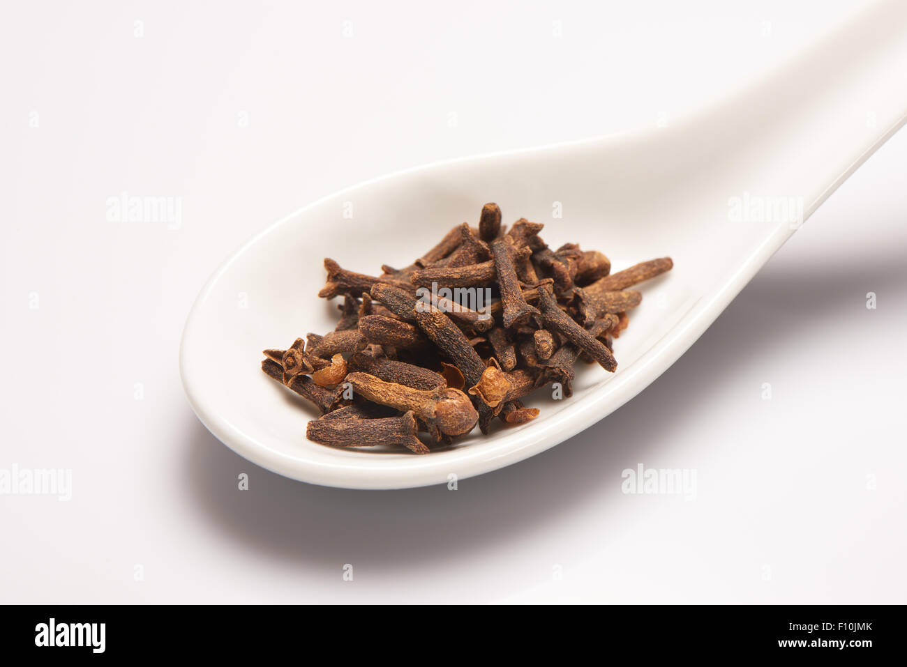 Cloves in white ceramic spoon on white background Stock Photo - Alamy