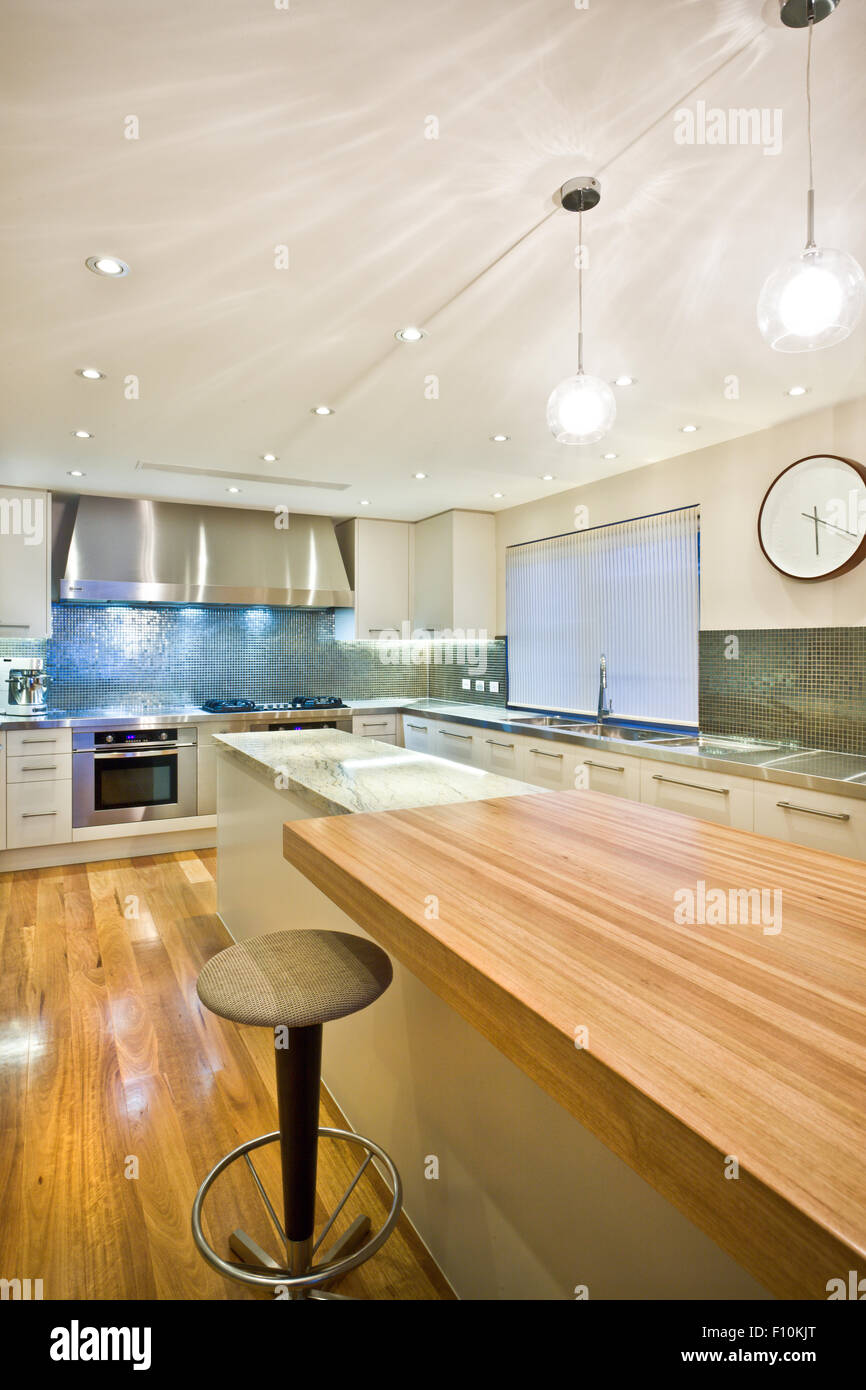 Spacious contemporary kitchen with a beuatiful clock hanging on a wall ...